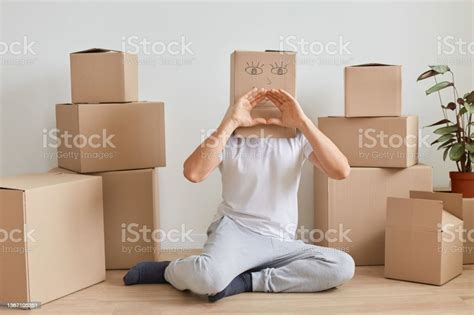 개인 소지품을 들고 골판지 상자 근처 바닥에 앉아 흰색 티셔츠를 입은 남자는 웃는 얼굴로 판지 상자를 들고 포즈를 취하고 손으로 심장 사랑 제스처를 보이고 재배치했다 35