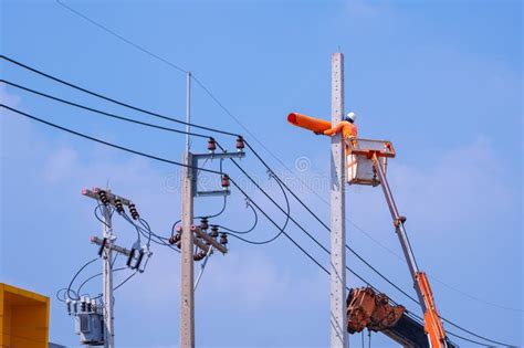 Electrician With Crane Truck Is Installing New Electrical Pole Against Blue Sky Background Stock