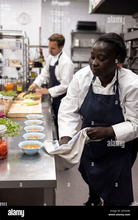 Chef Cleaning Kitchen Counter While Working In Commercial Kitchen Stock