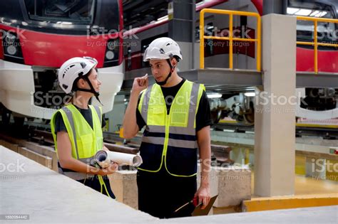 젊은 백인 엔지니어 남성과 여성이 만나 역 운송 및 기반 시설의 유지 보수를 계획하기 위해 전기 열차를 점검하고 검사관이 이야기하고 서비스 운송을 확인합니다 2명에 대한
