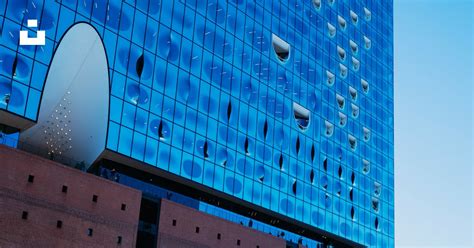 수역 옆에 파란색 파사드가 있는 고층 건물 사진 Unsplash의 무료 랜드마크 이미지