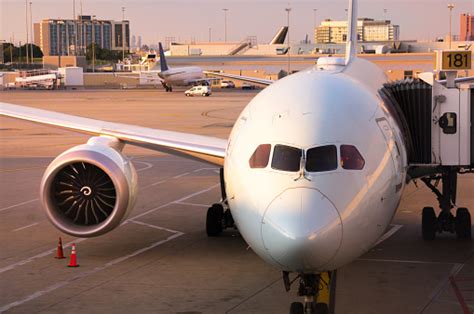 공항의 활주로에 있는 현대식 제트 비행기의 조종석은 일몰 태양 광선으로 밝혀졌습니다 승무원 객실의 미망인과 비행기 날개에 매달린 제트 엔진과의 클로즈업 공항에 대한 스톡
