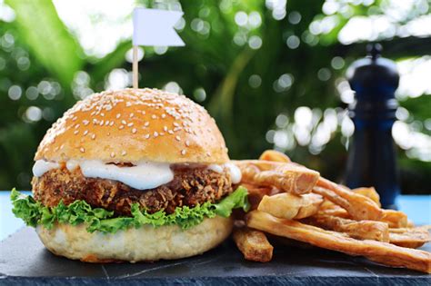 미식가와 미식가 석래 슬레이트 슬레이트에 집에서 만든 치킨 버거 참깨빵 빵 녹은 치즈 토마토 케첩과 양상추 감자 튀김 소금