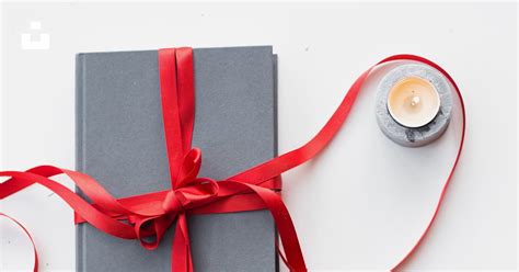 Teallight 촛불 옆에 빨간 리본으로 싸인 회색 책 사진 Unsplash의 무료 크리스마스 이미지