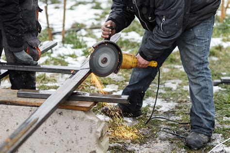 용접 철을 위한 앵글 그라인더 기계로 금속을 절단하는 작업자 원형 그라인더 디스크와 전기 스파크를 닫습니다 차폐 금속 아크 용접으로 울타리를 만드는 작업자 각도에 대한 스톡