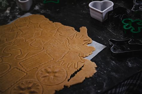 어두운 배경에 양피지 베이킹 종이에 원시 반죽에서 크리스마스 트리 스타 작은 남자 마음의 형태로 진저 브레드 쿠키를 잘라 맨 위