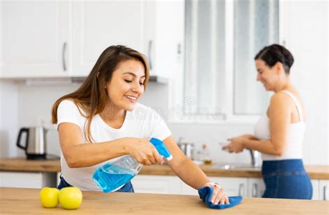 Femme Nettoyer Le Comptoir Dans La Cuisine Pendant Que Lami Lave La Vaisselle Image Stock