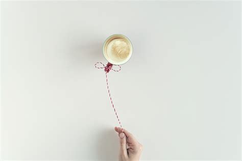 빨간 흰색 끈에 매달려 커피 컵으로 만든 풍선 공기 비행 풍선 또는 활에 묶여 꼬기와 여자 손 흰색 테이블입니다 크리스마스 개념입니다 창조적인 개념에 대한 스톡 사진 및