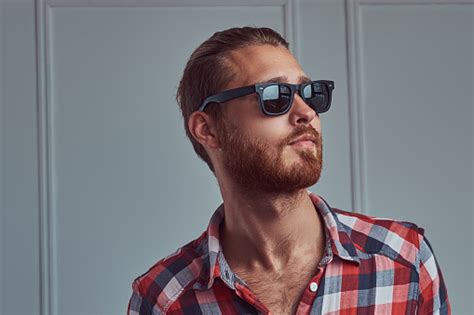 잘생긴 세련 된 빨간 머리 남자가 플 란 넬 셔츠와 선글라스 흰 벽에 스튜디오에 포즈 있다 개인 장식품에 대한 스톡 사진 및