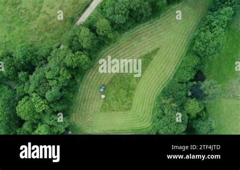 Top Down Aerial Of A Triangular Grass Field Being Cut In A Visually