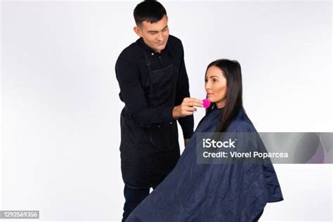 남성 메이크업 아티스트가 화장품 스폰지로 여성의 얼굴을 닦습니다 흰색 배경입니다 성별 고정관념 깨기 2명에 대한 스톡 사진 및