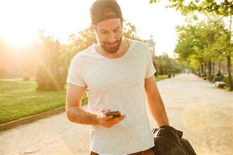 그린 파크에서 걷는 동안 길거리 옷을 입고 휴대 전화로 채팅을하는 유럽 수염 남자의 이미지 패션에 대한 스톡 사진 및 기타 이미지 패션 30 39세 Brand