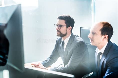 Rear View Of Stock Trader Analyzing Data At Multiple Computer Screens