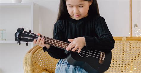 가정 환경 갈색 소파 검은색 우쿨렐레 귀여운 아이 기타 기타리스트 단순한 거실 대나무 소파 레저 레져 활동 머리띠 서 있는 소녀 소파 수직 쐈어