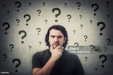 화가 나고 혼란스러워하는 젊은이의 초상화가 카메라에 의심스러워 보입니다 당황하고 의심 캐주얼 남자는 대답 호기심 얼굴을 기다리고 턱 아래에 손을 유지합니다 머리 주위에 여러