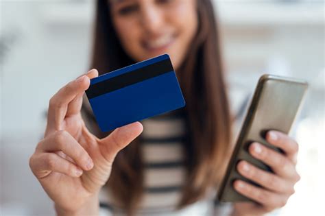 집에서 소파에 앉아 신용카드와 스마트폰으로 온라인 쇼핑을 하는 예쁜 젊은 여성 25 29세에 대한 스톡 사진 및 기타 이미지 25 29세 Brand Name