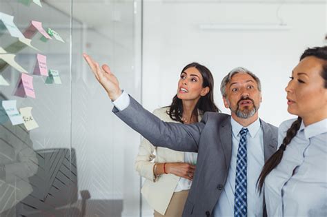 유리 벽에 차트를 작성하고 고집을 부림으로써 창조적 인 기업 사무실에서 작업 계획과 목표를 개발하는 공식적인 마모의 심각한