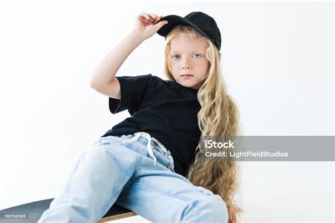 모자를 조정 하 고 스케이트 보드에 앉아 흰색 절연 하는 동안 카메라를 보고 긴 곱슬 머리를 가진 아름 다운 아이 T 셔츠에 대한 스톡 사진 및 기타 이미지 Istock