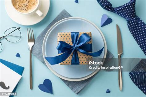 파스텔 블루 배경에 접시 커피 머그잔 수저 냅킨 리본 리본 넥타이 안경 우편 및 하트가 있는 선물 상자가 있는 멋진 아버지의 날 테이블 배열 0명에 대한 스톡 사진 및 기타