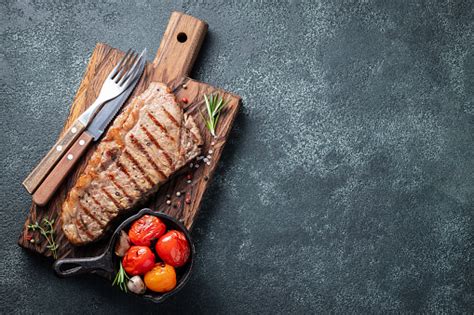 고추 마늘 소금 백 리 향와 구운 스테이크 Striploin 나무 보드에 제공 됩니다 어두운 돌 배경에서 저녁 식사 완성 된