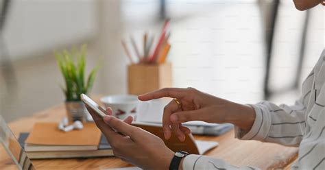 현대적인 사무실 배경의 나무 작업 책상에서 태블릿 앞에 앉아 스마트폰을 사용하는 쾌활한 여성의 측면 사진 사진 Unsplash의 손가락 포인팅 이미지