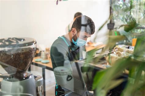 커피 공장의 라틴계 남성 직원이 고객을 위해 커피를 준비하는 바 안에 서 있습니다 기계류에 대한 스톡 사진 및 기타 이미지