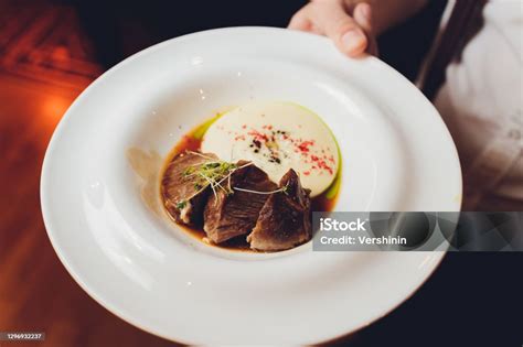 웨이터는 접시 맛있는 육즙 이 많은 고기 커틀릿 채소를 뿌린 으깬 감자 토마토와 양상추 잎의 신선한 건강한 샐러드를 들고 있습니다 가루로 빻은에 대한 스톡 사진 및 기타