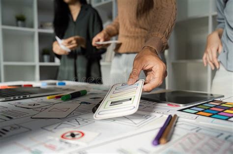 Creative Ux Ui Design Team Collaborating On Mobile App Wireframes In Modern Office Environment