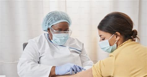 젊은 여성을 위한 예방 접종을 하는 의료 고문의 클로즈업 그녀가 테이블에 팔을 유지하는 동안 젊은 아가씨에게 주사를 준비하고있는 의사의 클로즈업 스톡 사진 사진