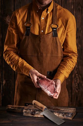 가죽 가운을 입은 정육점이 생 스테이크를 보유하고 있습니다 날고기 정육점 주인에 대한 스톡 사진 및 기타 이미지 정육점 주인 가죽 갈비 음식 Istock