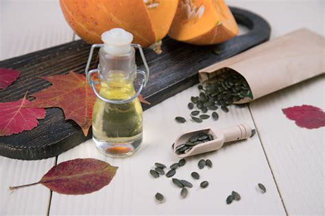 밝은 배경에는 흩어진 호박 씨앗이 있는 나무 숟가락 호박 기름 한 병 어두운 나무 판에 호박을 잘라냅니다 전통적인 오일에 대한