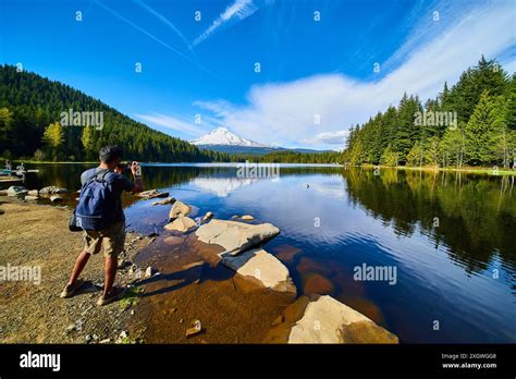 Mount Hood Reflection In Clear Lake With Photographer At Rocky Shore