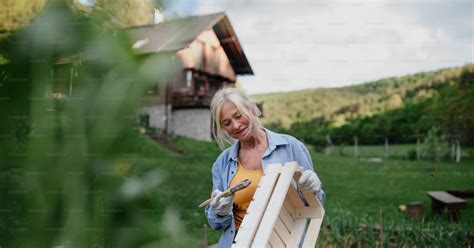정원에서 야외에서 나무 상자를 함침시키는 붓을 든 노인 여성 사진 Unsplash의 슬로바키아 이미지