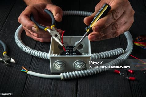 마스터 전기 기술자의 작업장에서 전기 연결 작업 중 전문 마스터 전기 기술자의 손 클로즈업 회색 정션 박스에 케이블 또는 와이어 설치 개체 그룹에 대한 스톡 사진 및 기타