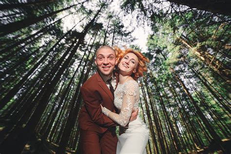 여름날 녹색 숲에서 행복한 세련된 커플 신혼 부부 긴 흰색 드레스와 빨간 양복을 입은 신랑이 포옹하고 있습니다 결혼식 날 25 29세에 대한 스톡 사진 및 기타 이미지