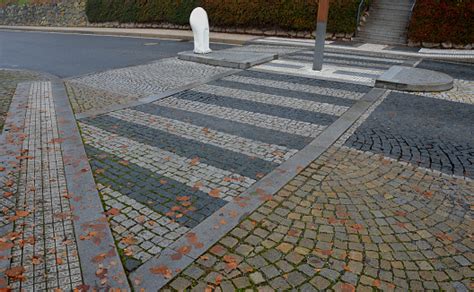 차선 사이에 섬을 나누는 보행자 횡단 거리를 따라 건조하고 사랑스러운 꽃으로 심어진 도로 표시가있는 아치 원예 호화로운 돌 연석과 산책로 포장 0명에 대한 스톡 사진 및