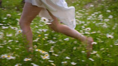A Woman In A White Dress Running Through A Field Of Daisies Photo