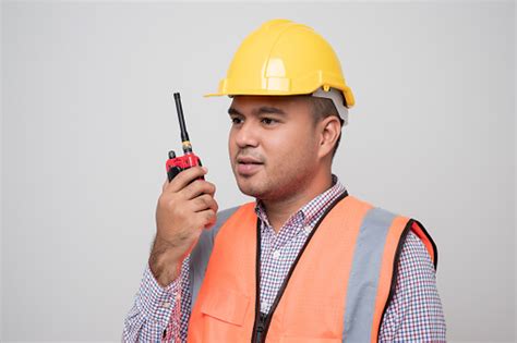 아시아 토목 엔지니어는 스튜디오에서 작업을 제어하기 위해 라디오 무전기와 함께 작동합니다 고립된 흰색 배경에 단단한 모자를 쓰고 있는 작업자 개발에 대한 스톡 사진 및 기타