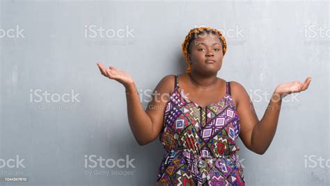 오렌지 입고 회색 그런 지 벽에 젊은 아프리카계 미국인 여자에 발생 하는 손과 팔을 우 둔 하 고 혼란 스 러 워 식 머리 띠 의심 개념입니다 땋은 머리에 대한 스톡 사진