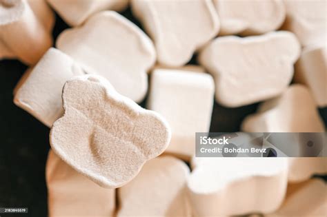 푹신푹신하고 질감이 있는 뼈 모양의 흰색 마시멜로가 부드러운 자연광 아래 아무렇게나 배열되어 있는 클로즈업 그림자는 깊이를