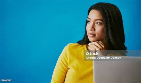파란 배경에 대한 스튜디오에서 그녀의 책상에 앉아있는 동안 사려 깊게 보이는 매력적인 젊은 여성의 자른 샷 노트북에 대한 스톡 사진 및 기타 이미지 Istock