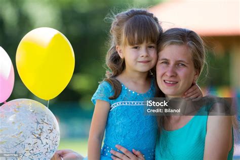 젊은 금발 의 행복한 어머니 포옹 사랑스럽고 보호 그녀의 작은 예쁜 유치원 딸 소녀와 흐린 보케 배경에 밝은 풍선 행복한 가족 관계와 사랑 개념 금발 머리에 대한 스톡 사진