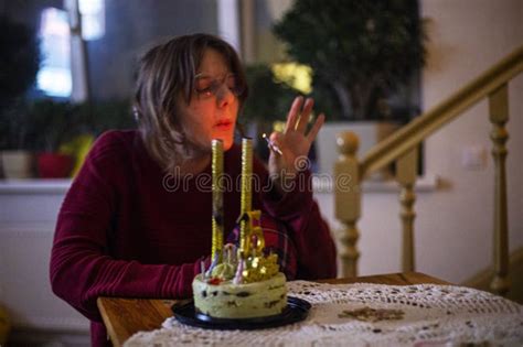 Teenage Girl Blowing Out Candles On Her 15th Birthday Cake Surrounded