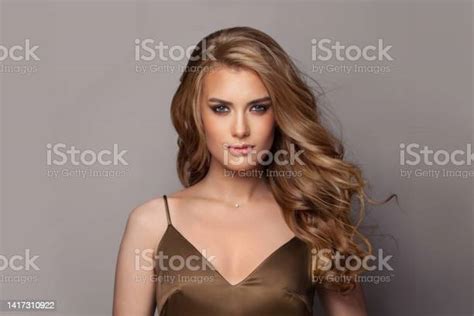 길고 볼륨이 반짝이는 물결 모양의 머리카락을 가진 쾌활한 귀여운 젊은 여성 곱슬 머리 스타일을 가진 아름다운 모델 털에 대한