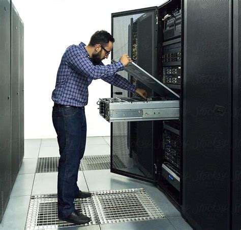 Technician Performing Maintenance Tasks In A Server Room Rack By Stocksy Contributor Acalu