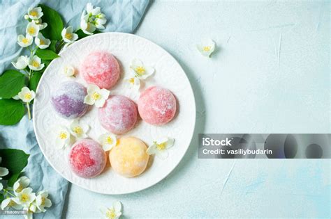 쌀 반죽에 여러 가지 빛깔의 일본식 아이스크림 떡과 콘크리트 파란색 배경에 자스민 꽃 화이트 플레이트에 일본 전통 디저트 복사 공간이 있는 맨 위 뷰입니다 플랫 레이 0명에