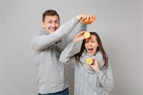 재미 있는 커플 여자 입은 회색 스웨터 스카프 함께 오렌지 레몬 회색 벽 배경 스튜디오 초상화에 고립 된 보류 건강 한 생활 습관 병 아픈 처리 추운 계절 개념입니다 복사