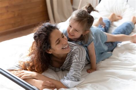 Mamá Joven E Hija Pequeña Se Relajan En El Dormitorio Foto De Archivo