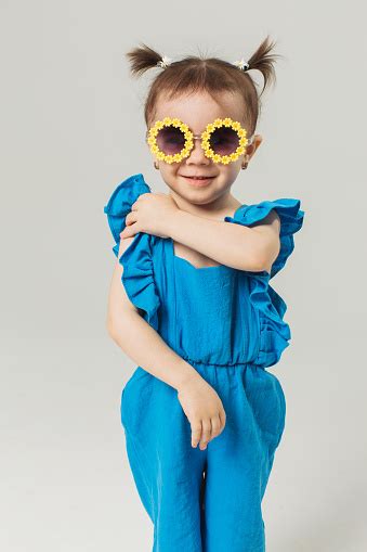 선글라스를 끼고 하얀 배경에 스튜디오에 있는 파란 정장을 입은 금발의 여자 아기 아이 어린 시절 헤어 롤빵 헤어 스타일 여름 패션 선글라스에 대한 스톡 사진 및 기타 이미지