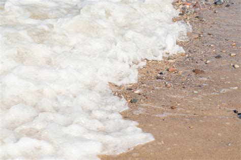 자갈 해변에 흐르는 하얀 거품이 있는 바다 파도의 클로즈업 해변에서의 해변 휴가와 가족 주말을 주제로 수정처럼 맑은 물과 바다 바위가 있는 배경 0명에 대한 스톡 사진 및